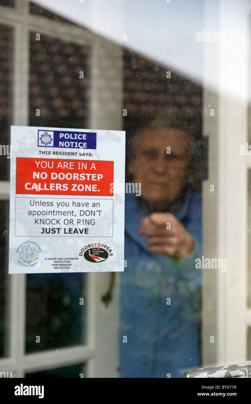 vulnerable elderly woman pointing at a front door warning notice to ...