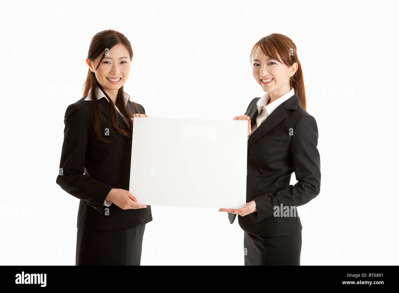 Two businesswomen holding board Stock Photo - Alamy