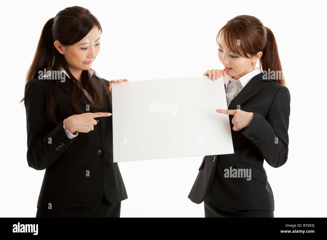 Two businesswomen holding board Stock Photo - Alamy