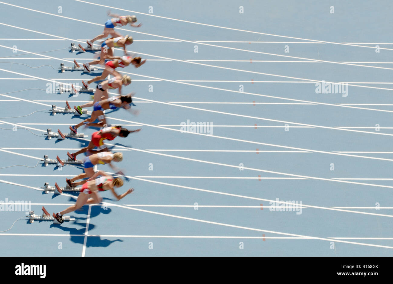 start of a womens sprinter race on blue running track Stock Photo - Alamy