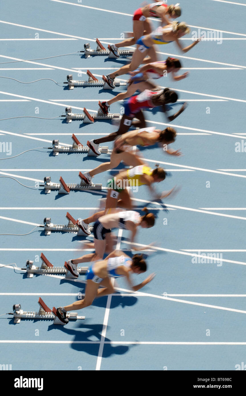 start of a womens sprinter race on blue running track Stock Photo - Alamy
