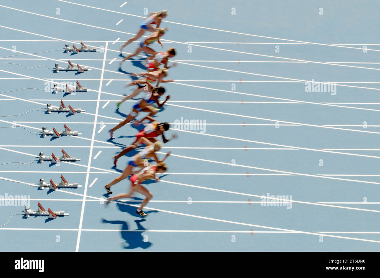 start of a womens sprinter race on blue running track Stock Photo - Alamy
