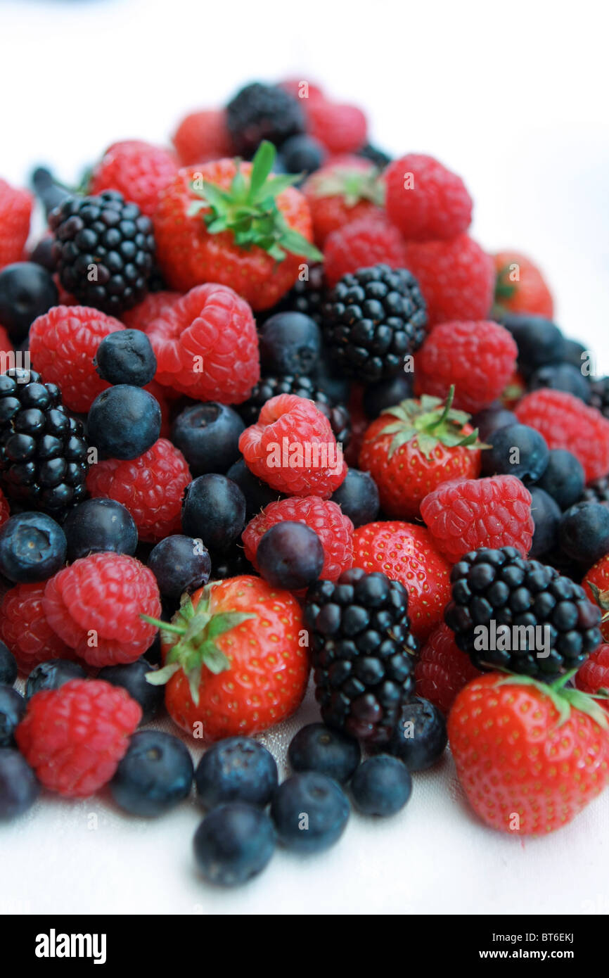 A pile of strawberries raspberries blackberries and blueberries against ...