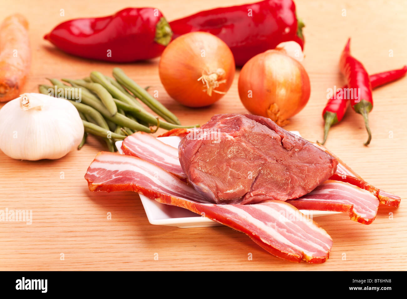 raw meat and bacon stripes on a wooden table Stock Photo - Alamy
