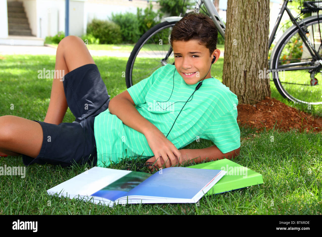 Teen smiling boy studying book garden headphones grass tree sitting ...