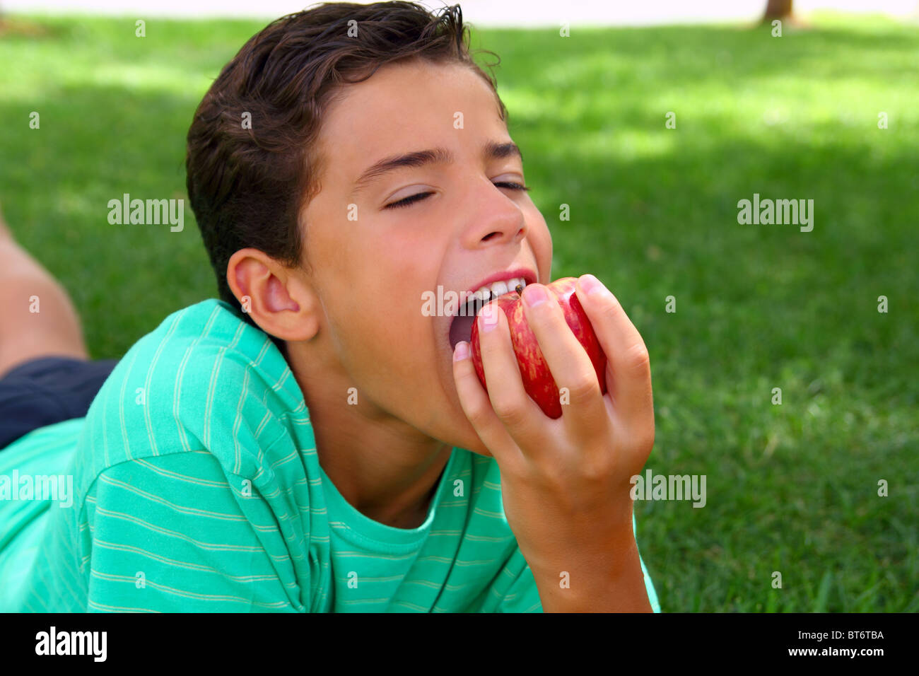 boy teenager eating red apple laying on garden grass outdoors Stock ...