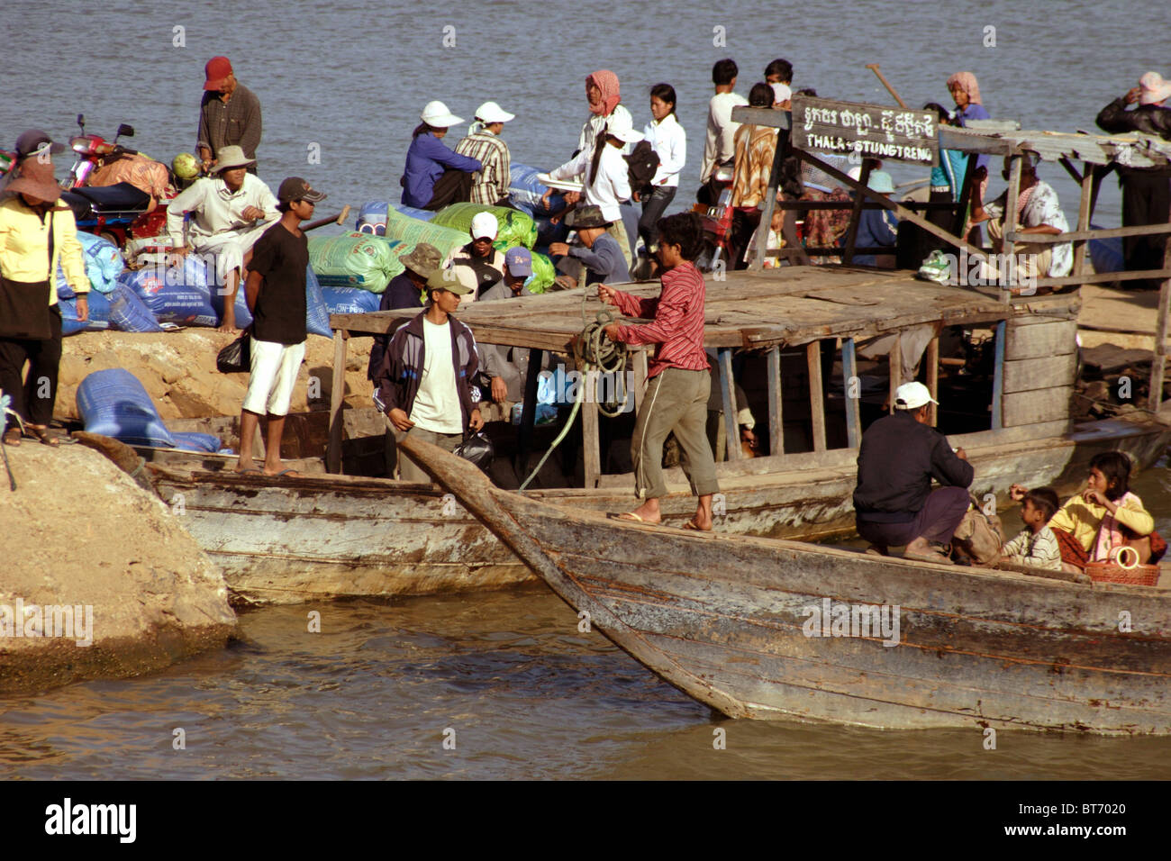 A young boy worker is throwing a rope to a ferry boat that is arriving ...