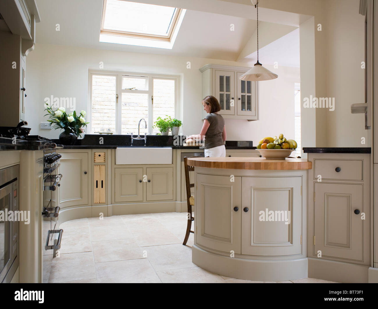 Woman in traditional kitchen extension with fitted cream units Stock ...