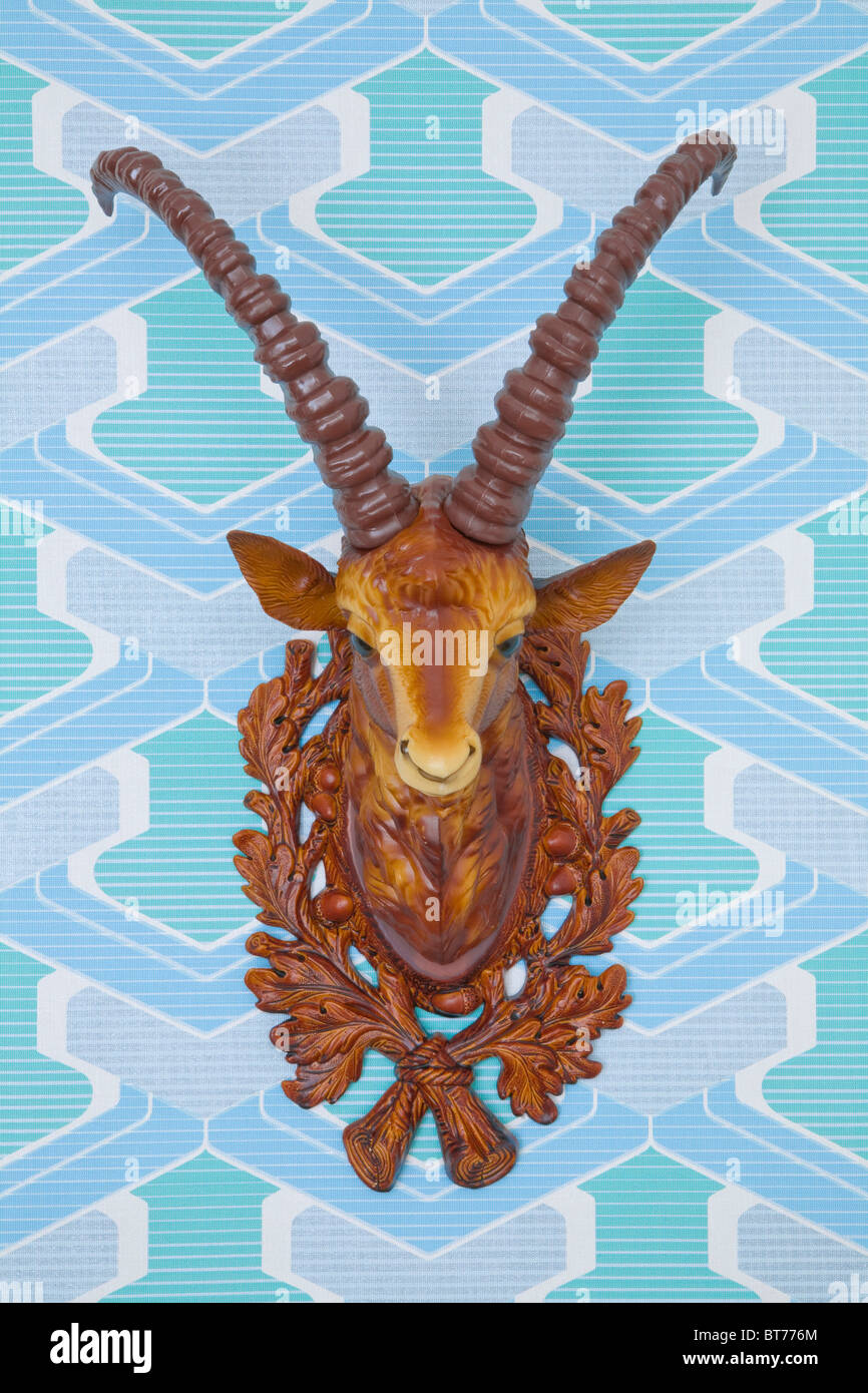 Plastic head of an ibex mounted on kitschy wallpaper from the 1960s or ...