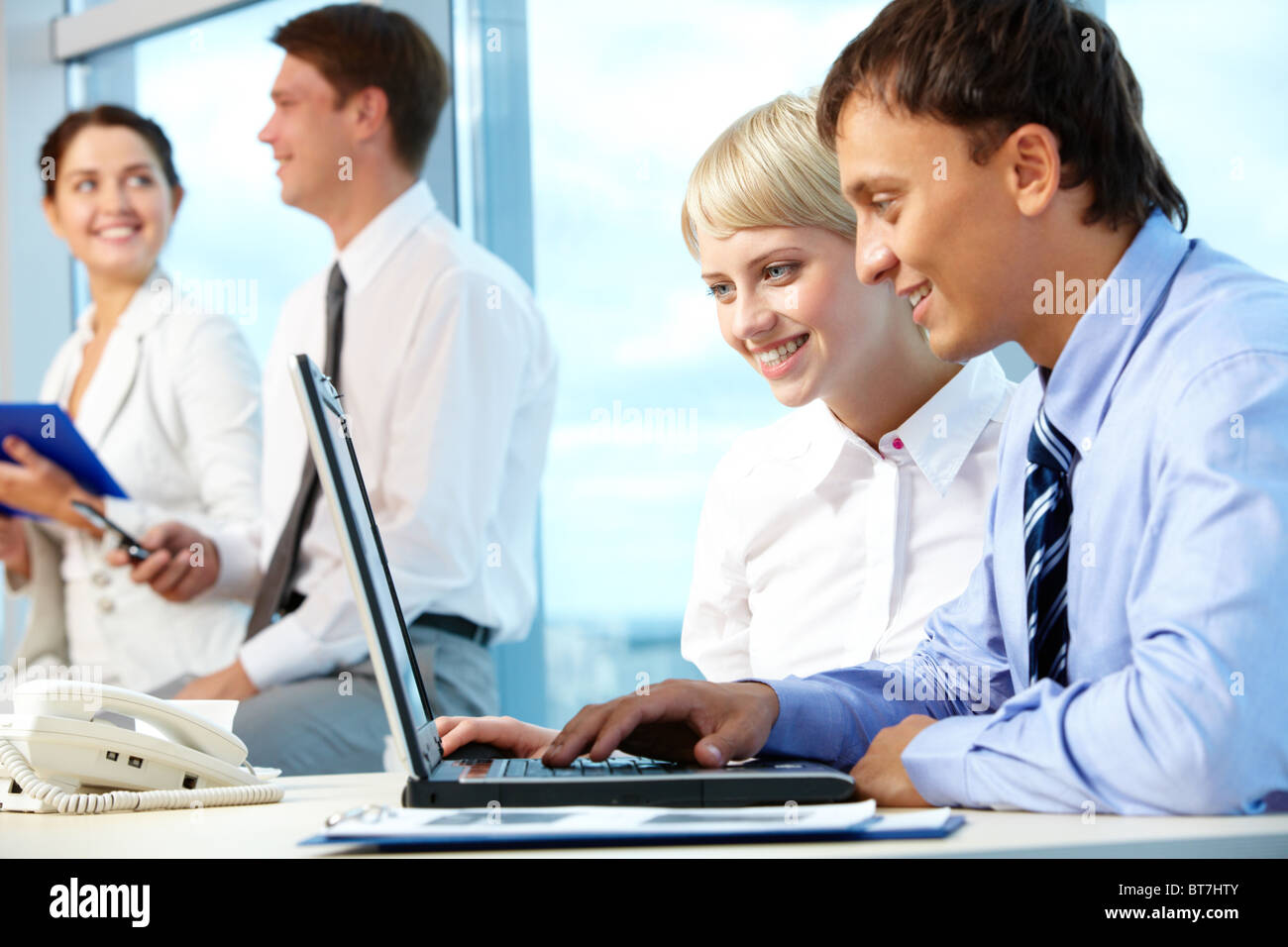Portrait of executive partners looking at laptop display while working ...