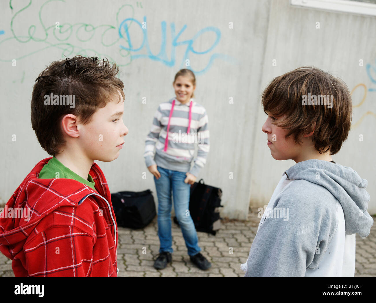 Two boys arguing in the schoolyard, a girl watching Stock Photo - Alamy