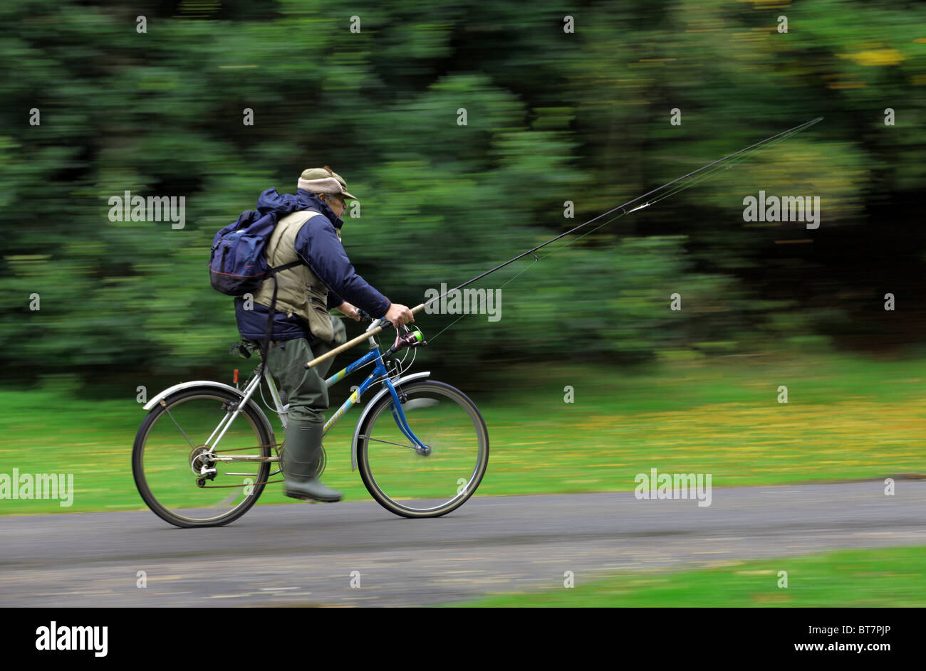 Angler travelling to go fishing on his bicycle with his rod in the UK ...