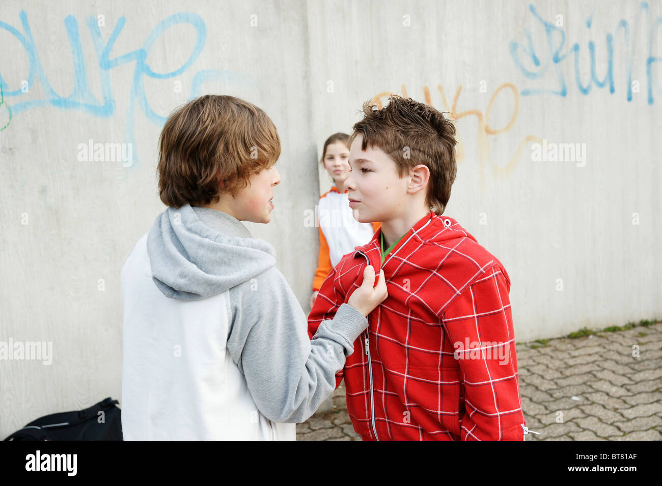 Two boys arguing in the schoolyard, a girl watching Stock Photo - Alamy