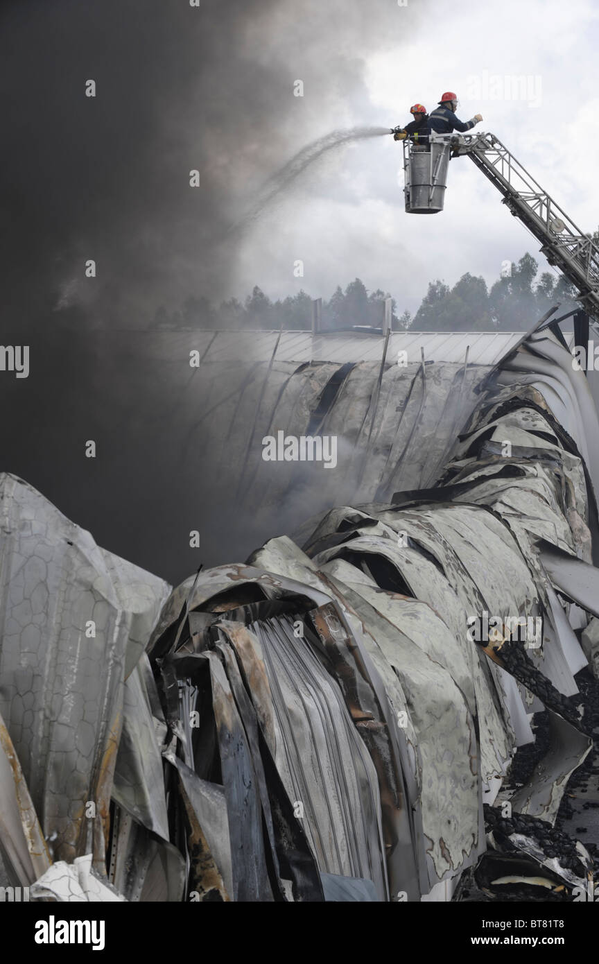 Firemen on an extension ladder fighting a massive factory fire amidst ...