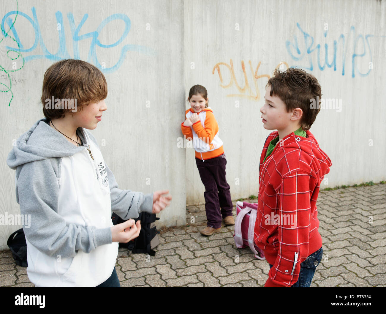 Two boys arguing in the schoolyard, a girl watching Stock Photo - Alamy