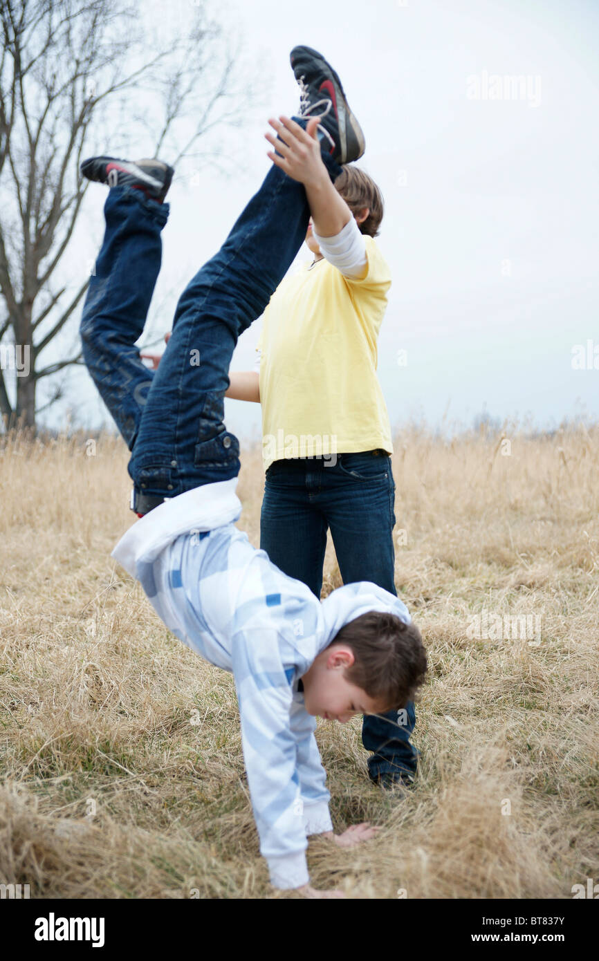 Two boys practicing a handstand in a meadow Stock Photo - Alamy