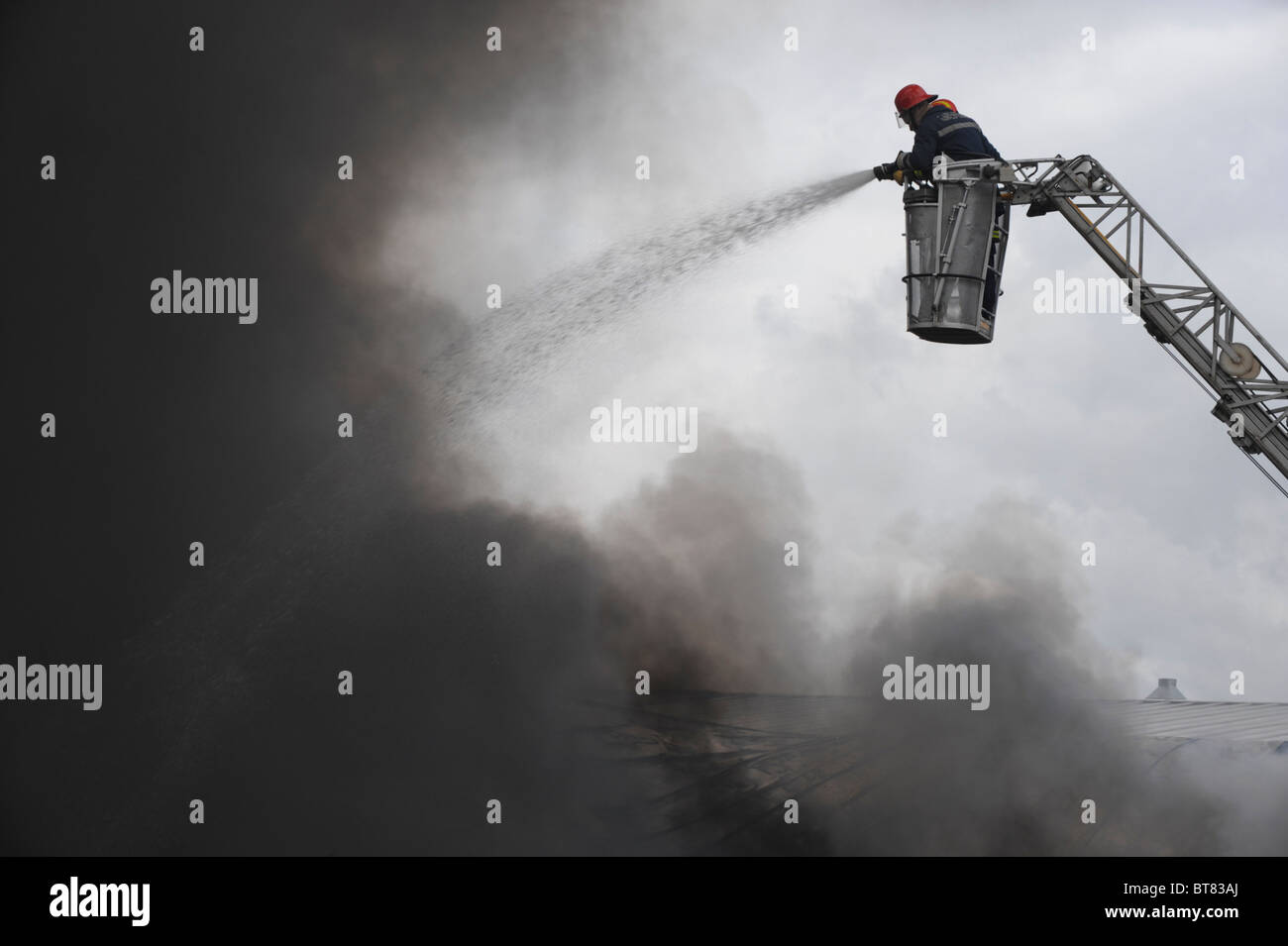 Firemen on an extension ladder fighting a massive factory fire amidst ...