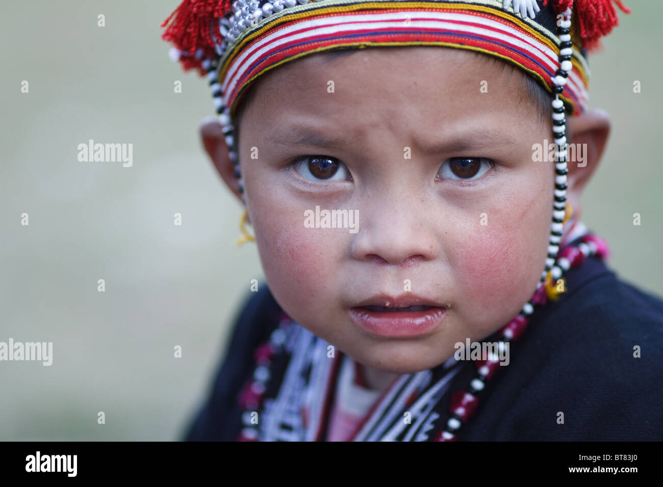 Red Dzao minority child wearing traditional clothing peers at the ...