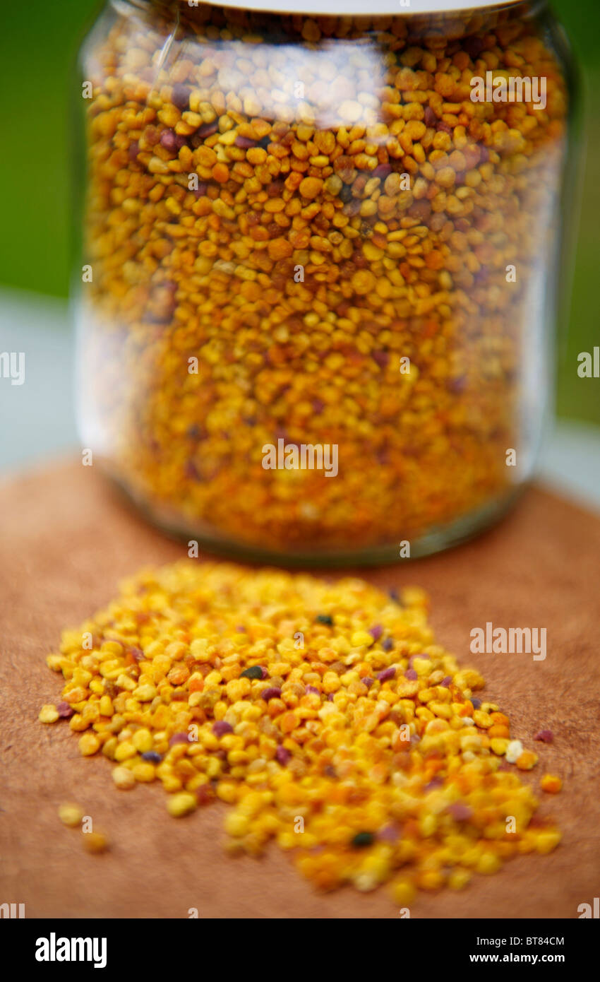 Glass jar full of bee pollen with a collection of pollen in front on ...