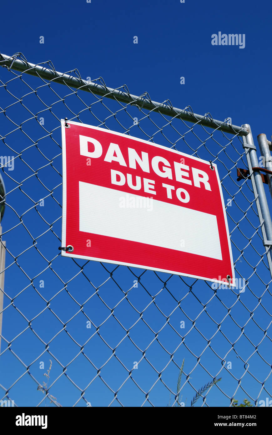 A blank sign warning of unknown danger posted on a chain link fence ...