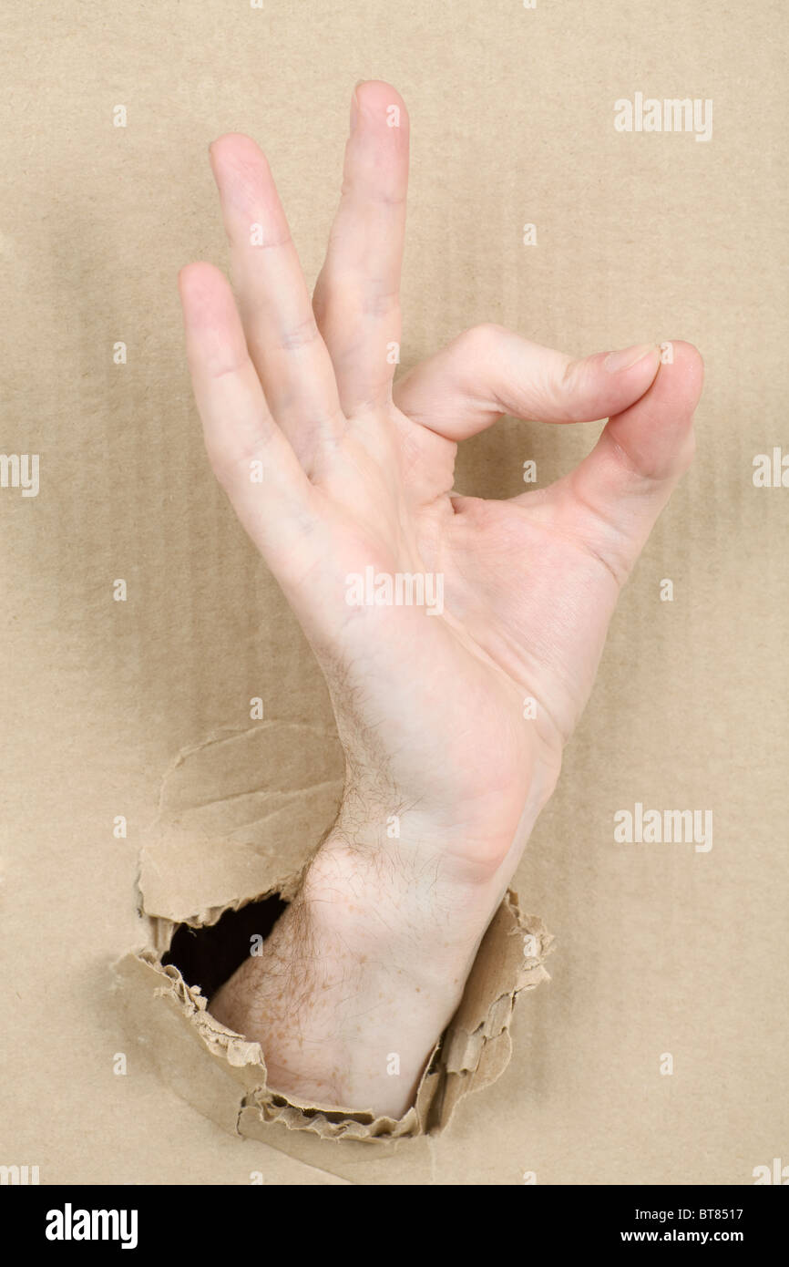 Gesture male hand through from hole in cardboard Stock Photo - Alamy