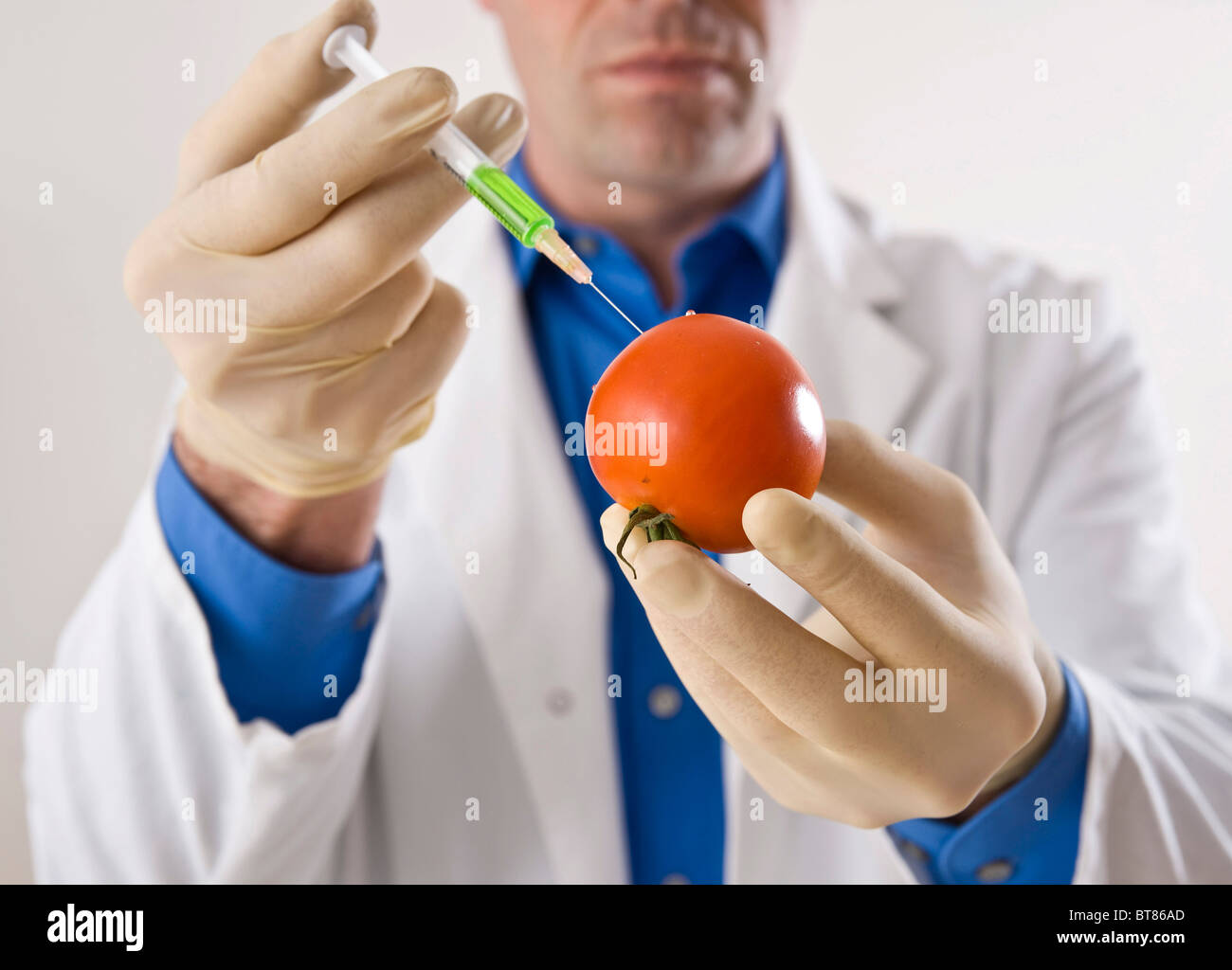 Man in a laboratory injecting liquid into a tomato Stock Photo - Alamy