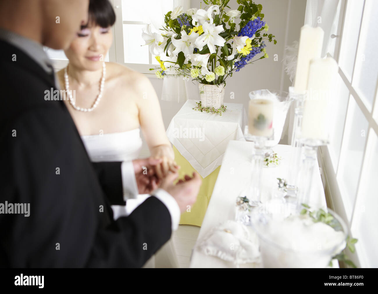 Groom putting a ring on bride's finger Stock Photo - Alamy