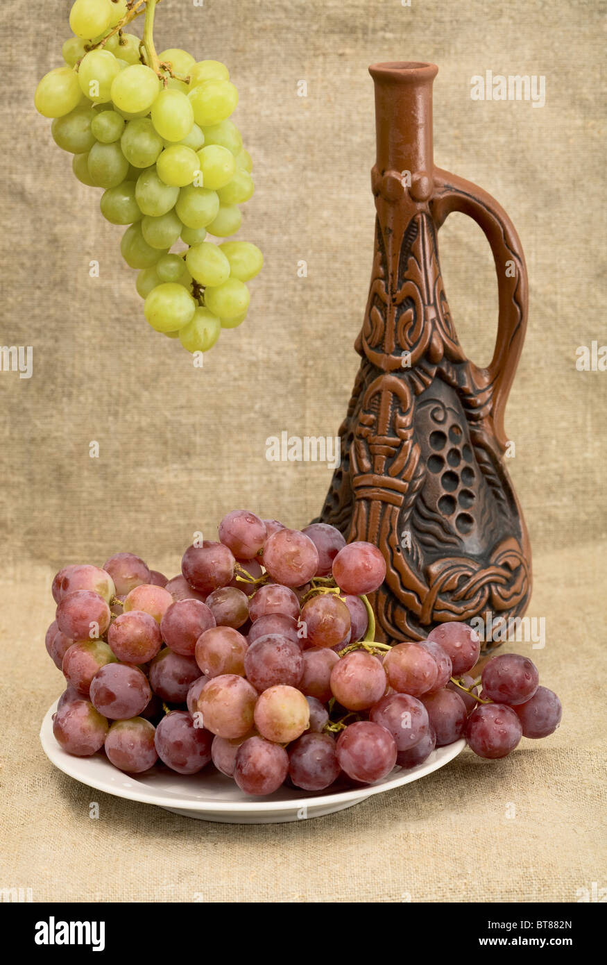Ceramic bottle and grapes on the sacking background Stock Photo - Alamy