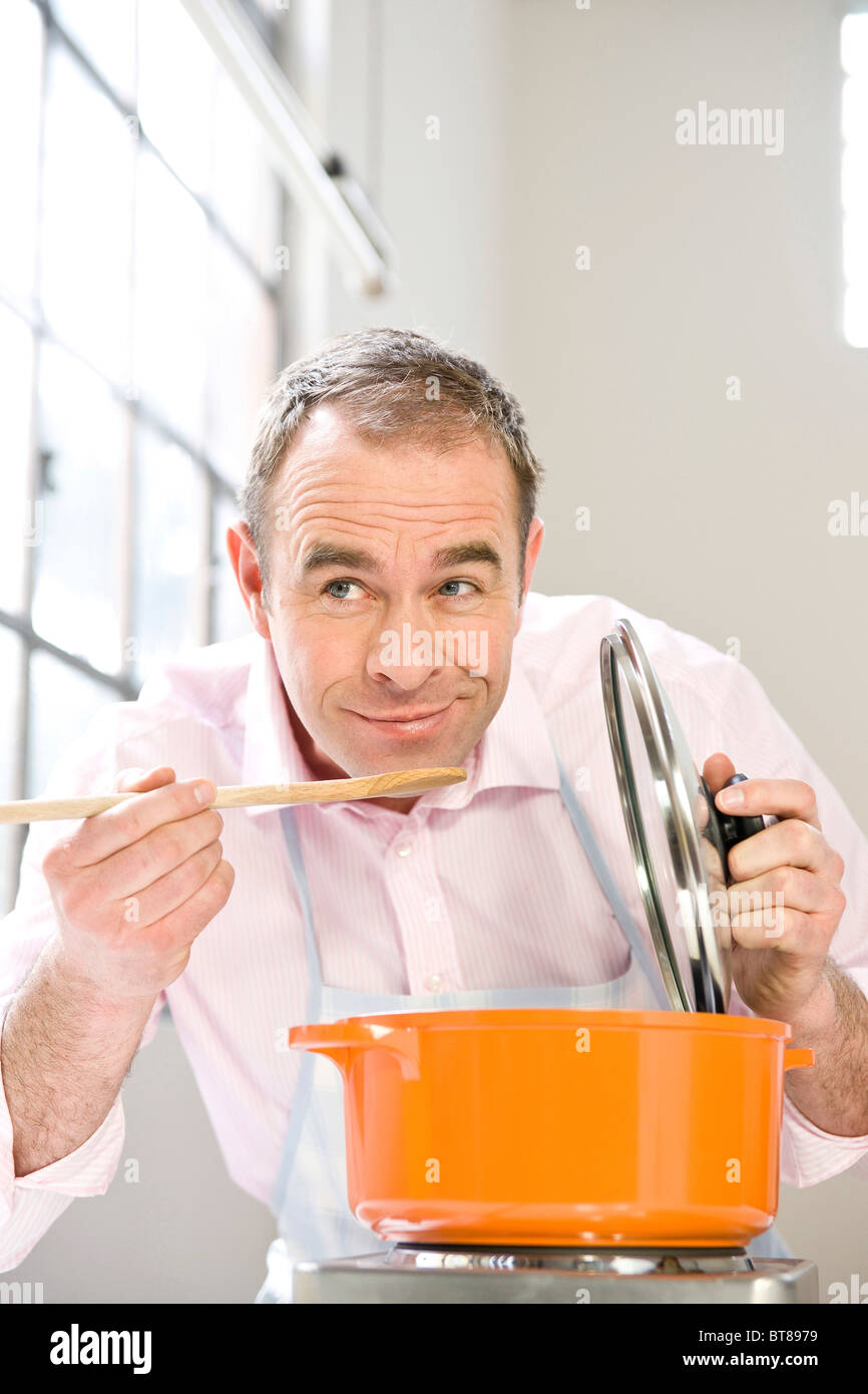 Man tasting something from a saucepan Stock Photo - Alamy