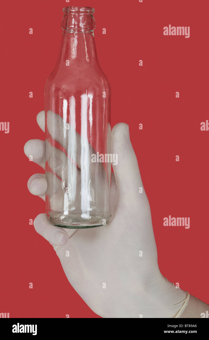Glass bottle on hand on the red background Stock Photo - Alamy