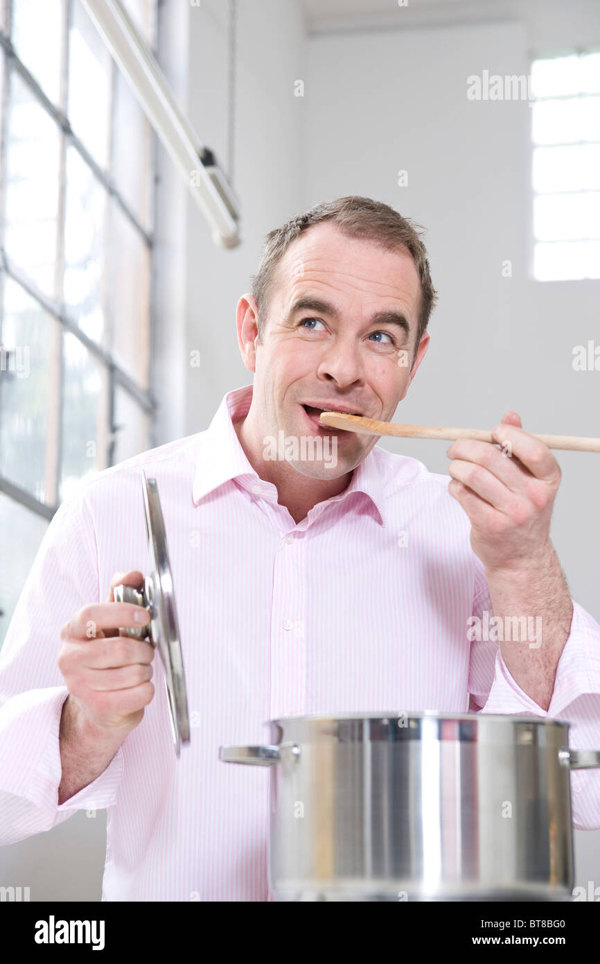Man tasting something from a saucepan Stock Photo - Alamy
