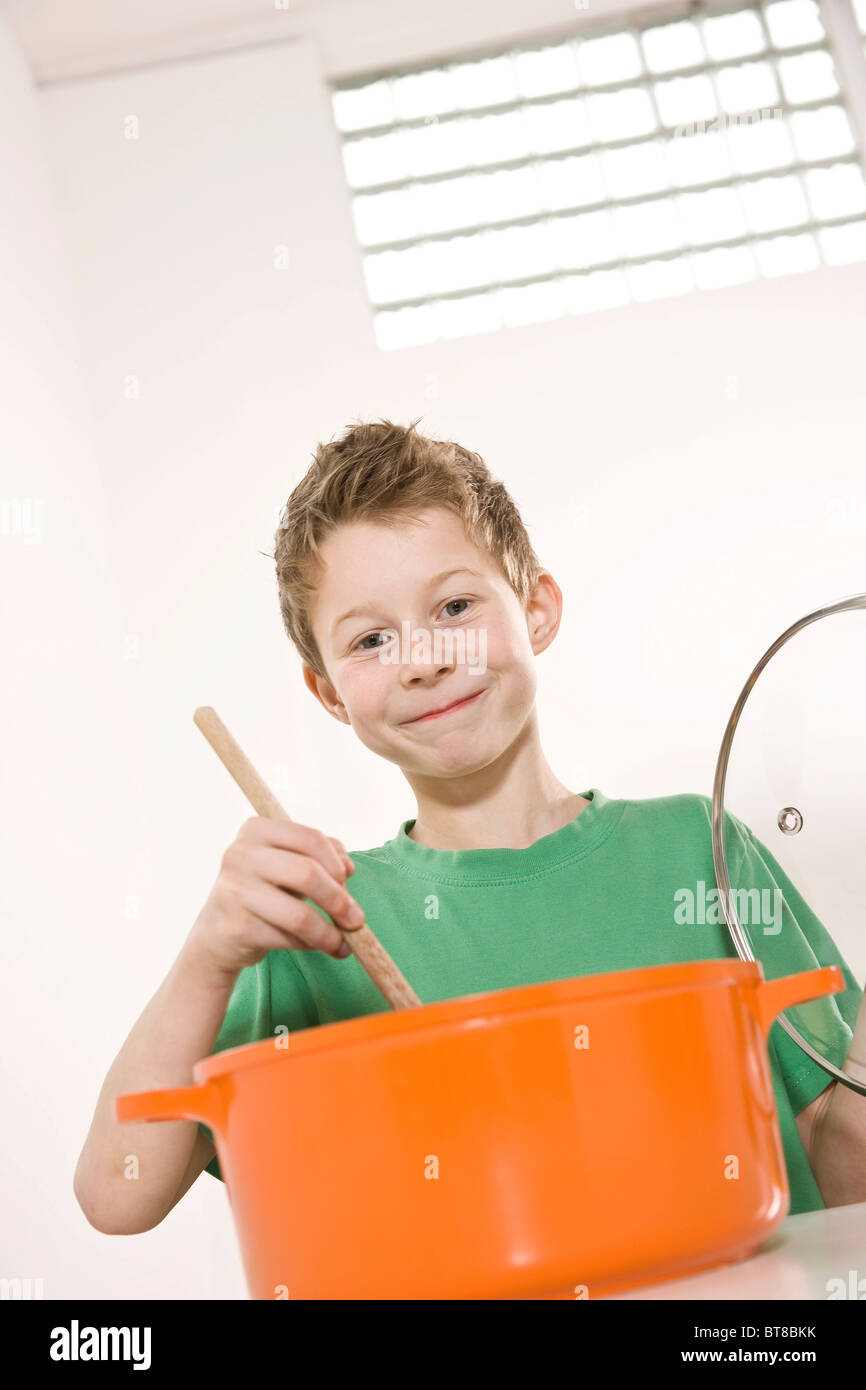 Boy smiling while stirring in a pot Stock Photo - Alamy