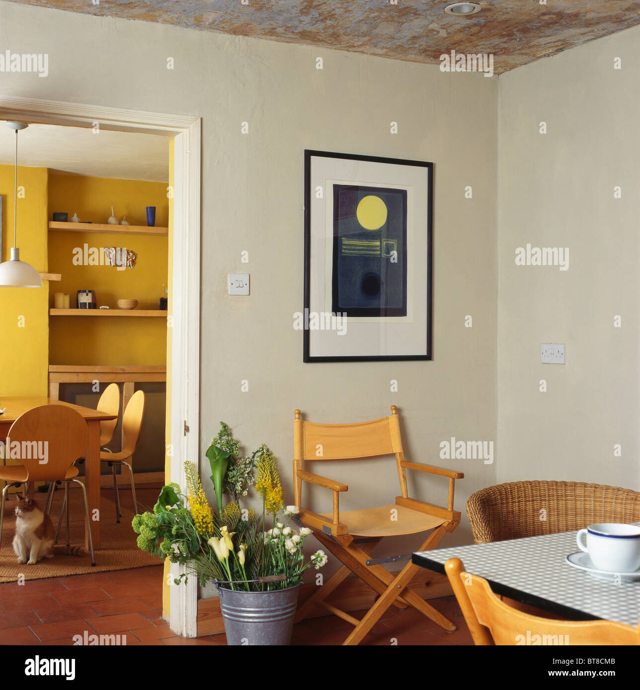 Modern picture above yellow director's chair in cream cottage kitchen ...