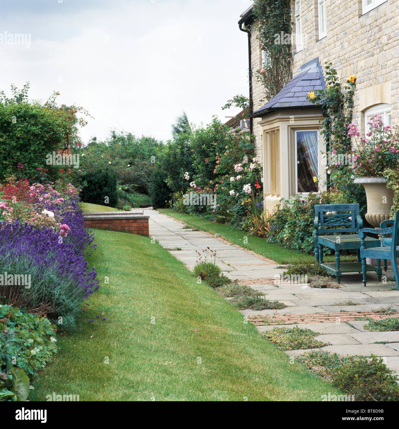 Summer border and mown grass path beside stone path in front of ...