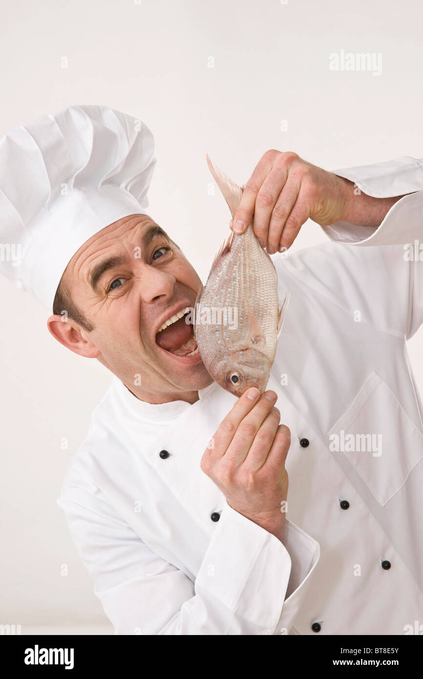 Cook biting into a raw fish Stock Photo - Alamy