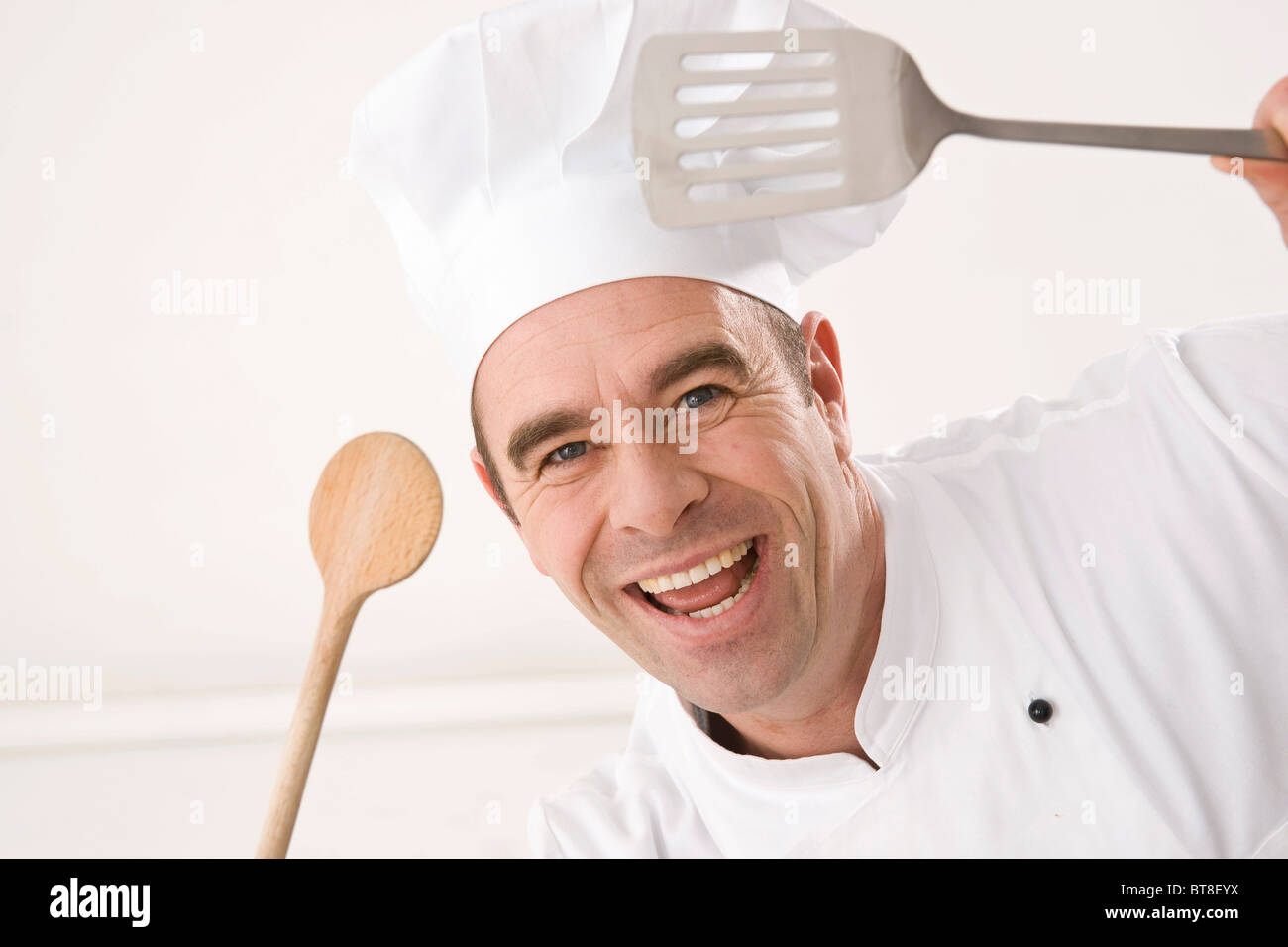 Laughing cook holding a cooking spoon and a ladle Stock Photo - Alamy