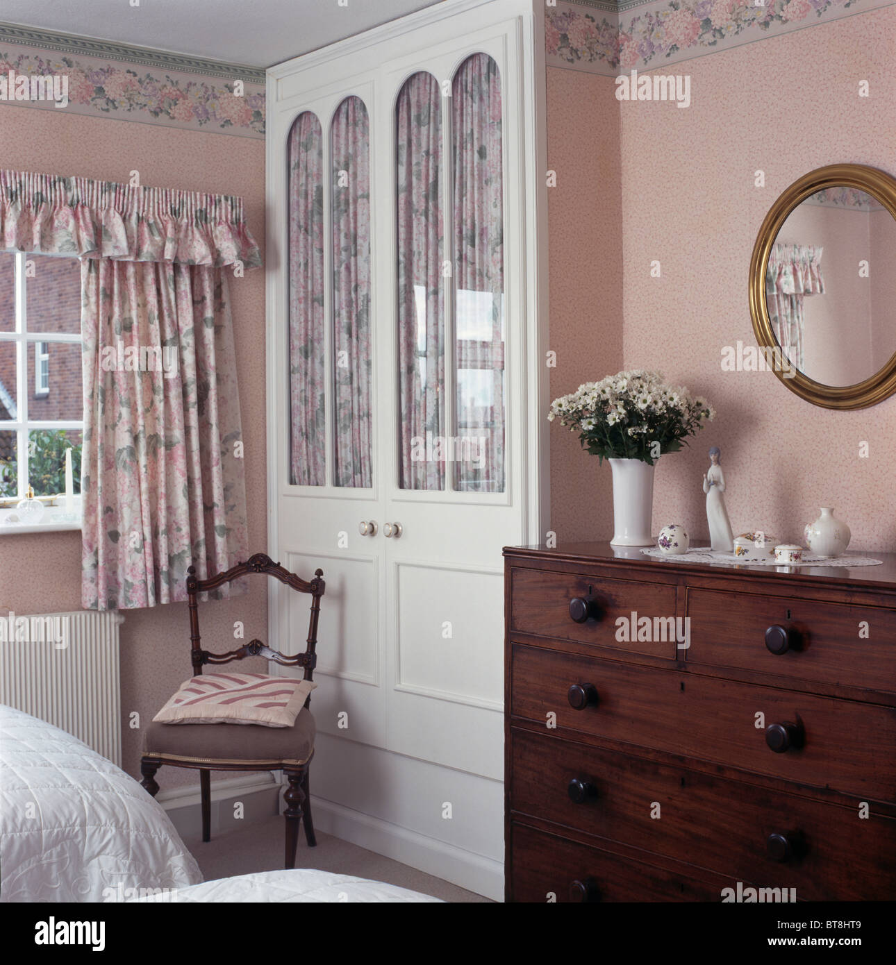 Fitted wardrobe with curtains behind glazed doors in cottage bedroom ...