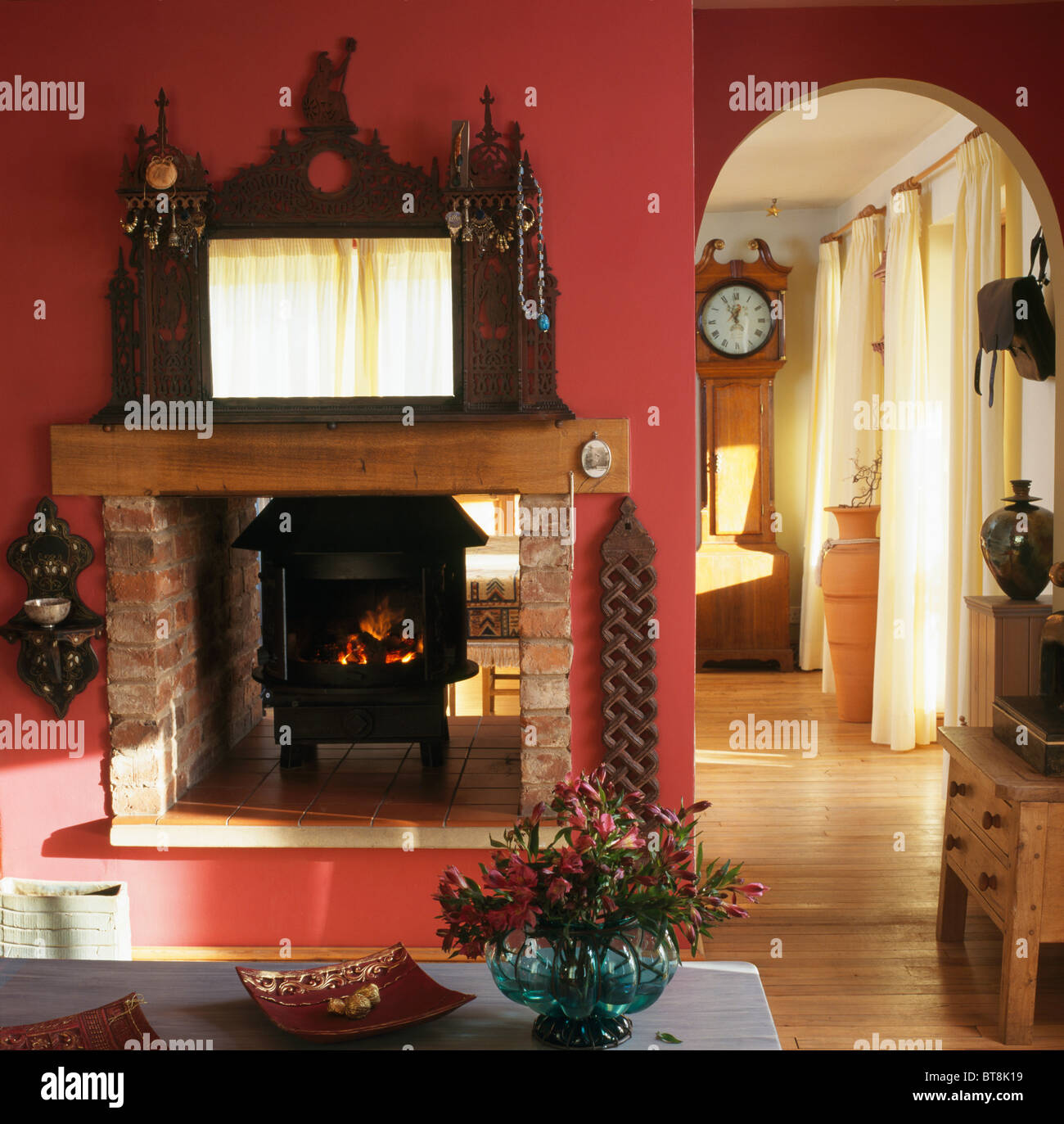 Carved wood mirror above open fireplace with black cast-iron stove in ...