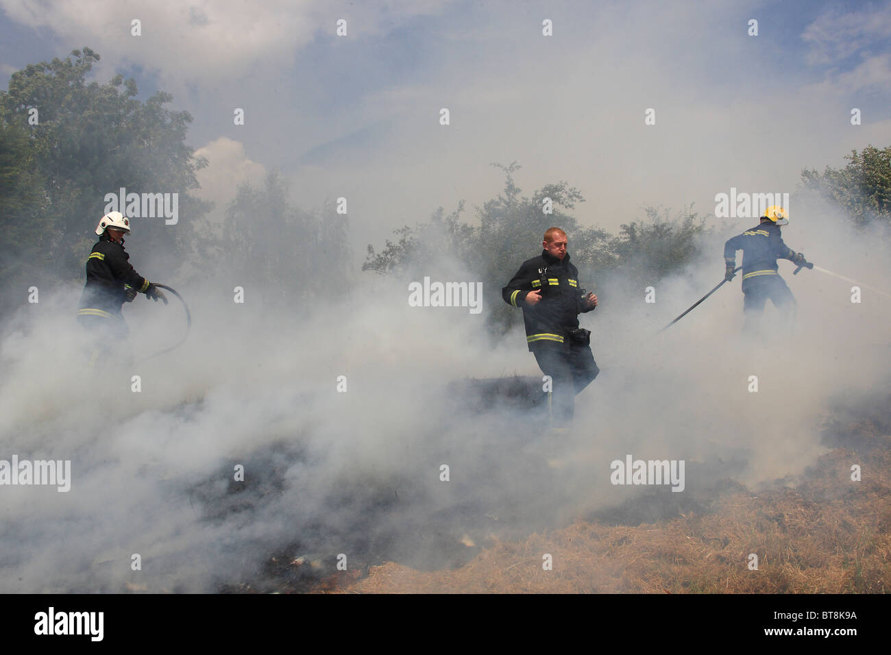 Firemen tackling a smokey field fire Stock Photo - Alamy
