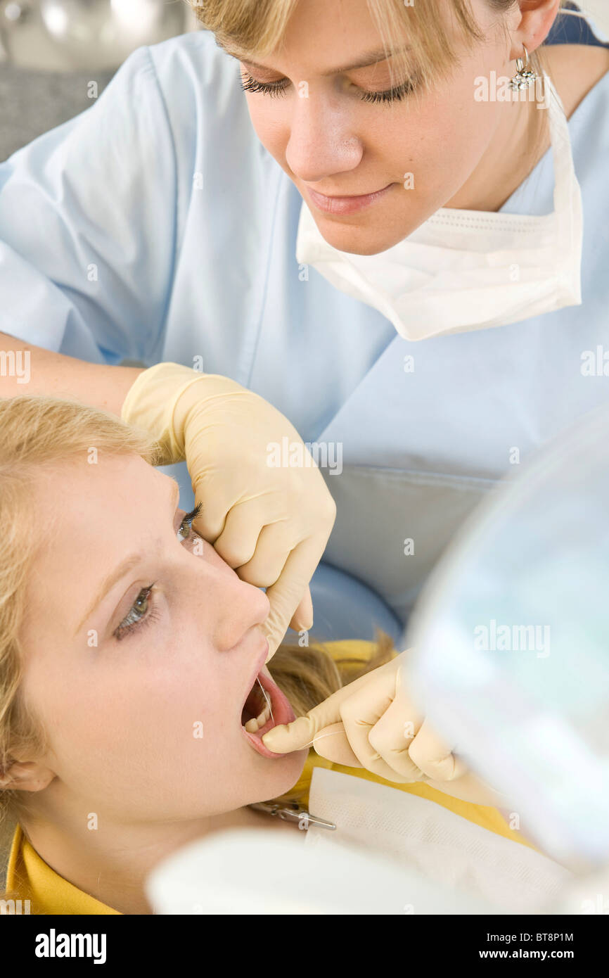 Dental nurse cleaning a patient's teeth with dental floss Stock Photo ...