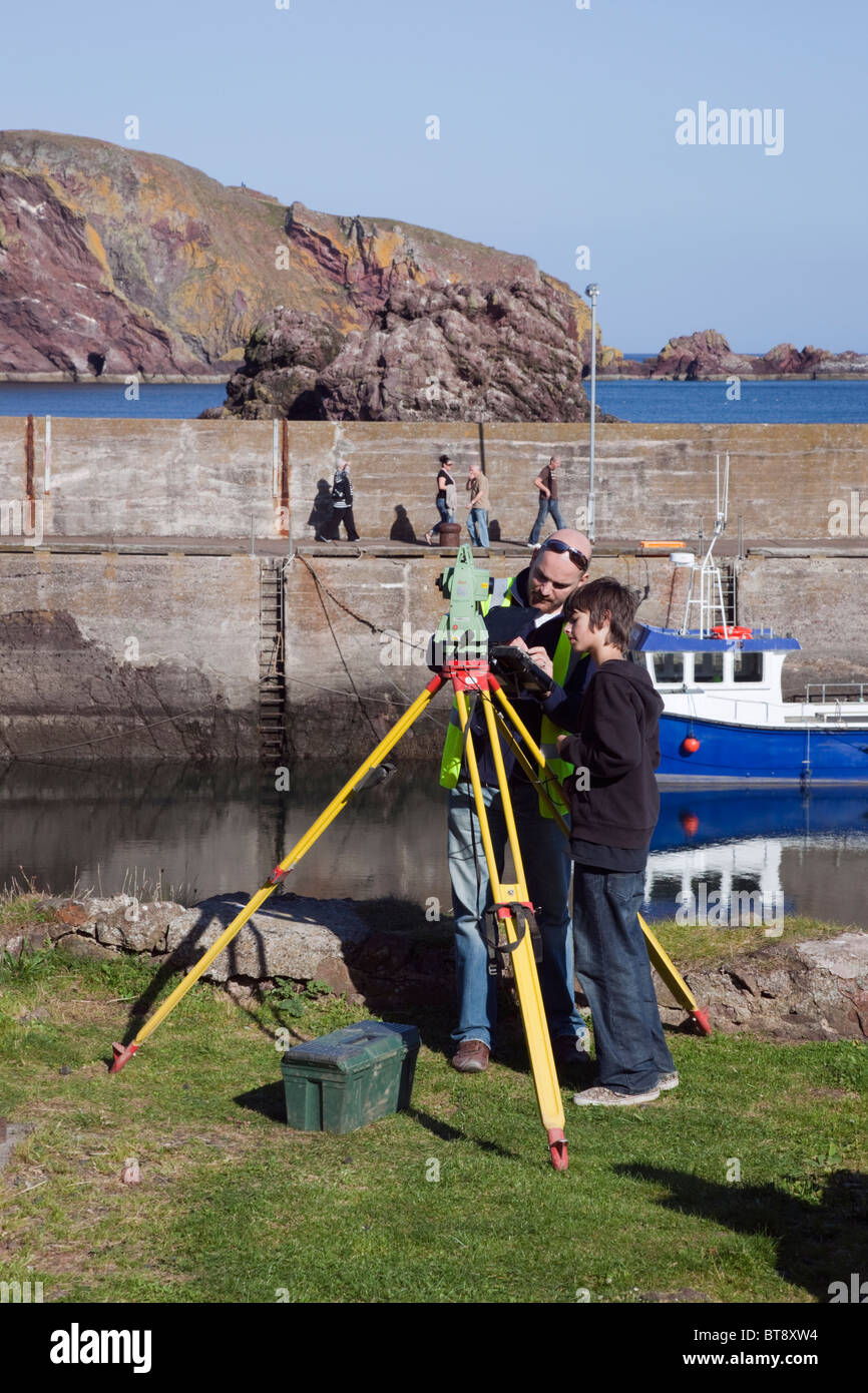 Man teaching a young boy how to use a Leica theodolite for surveying ...