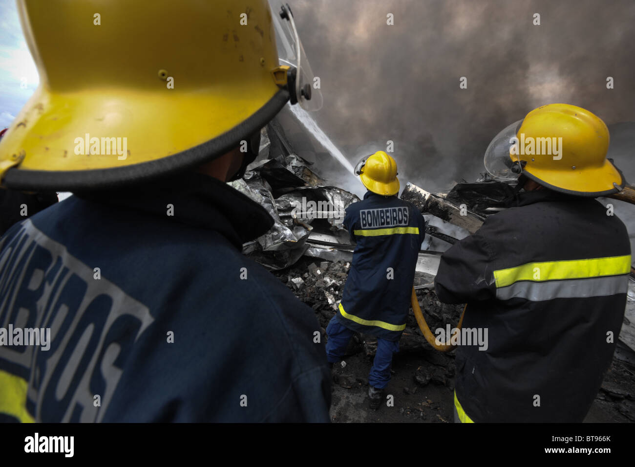 Three firemen help each other while fighting a factory fire Stock Photo ...