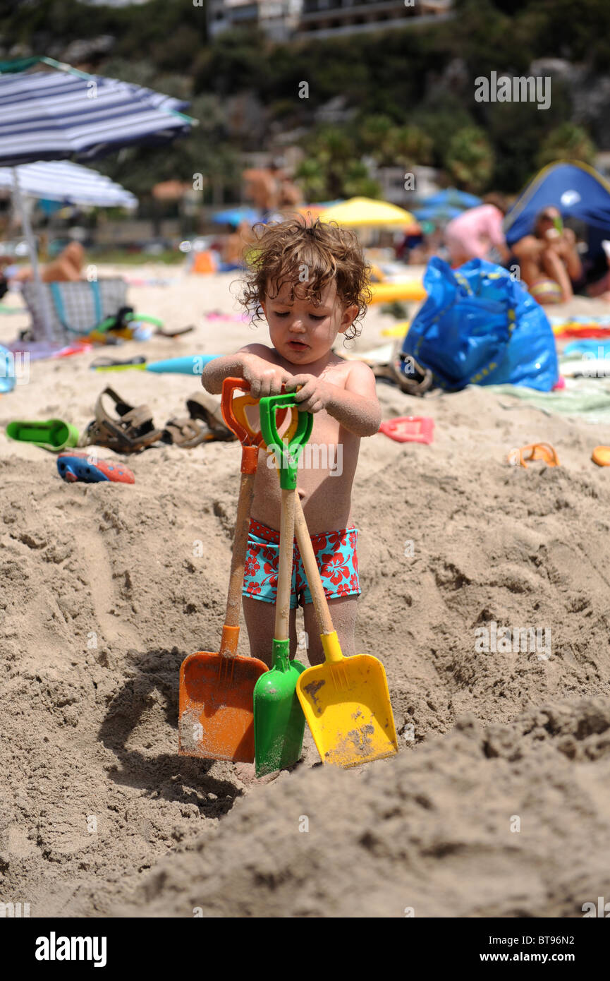 little girl playing with spades in the sand Stock Photo - Alamy