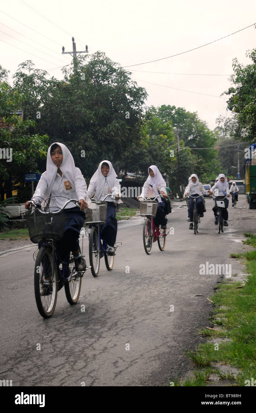 Muslim girls in school uniform riding their bicycles to school ...