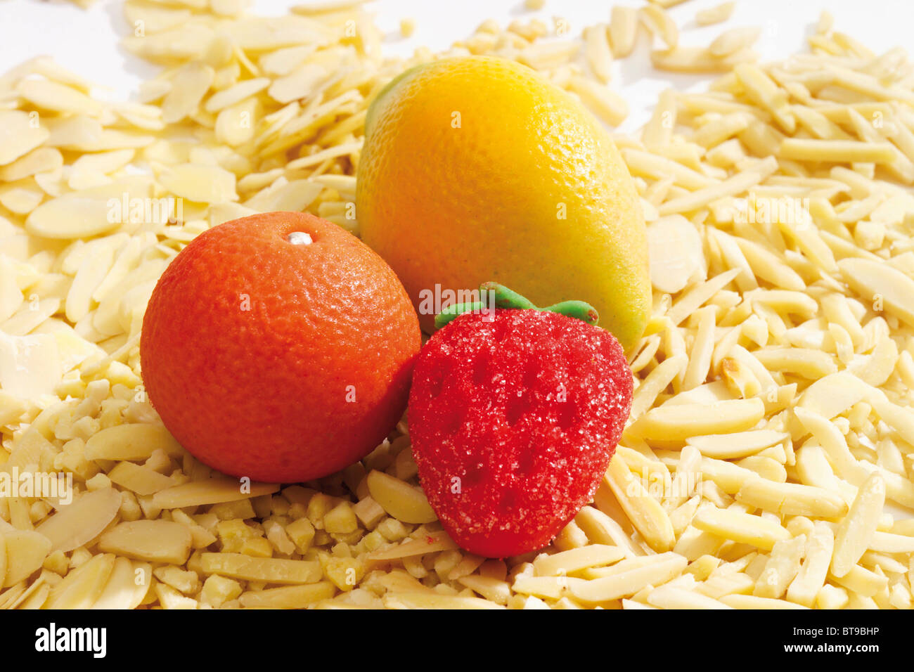 Marzipan fruits, strawberry, orange and lemon on a bed of almonds Stock ...