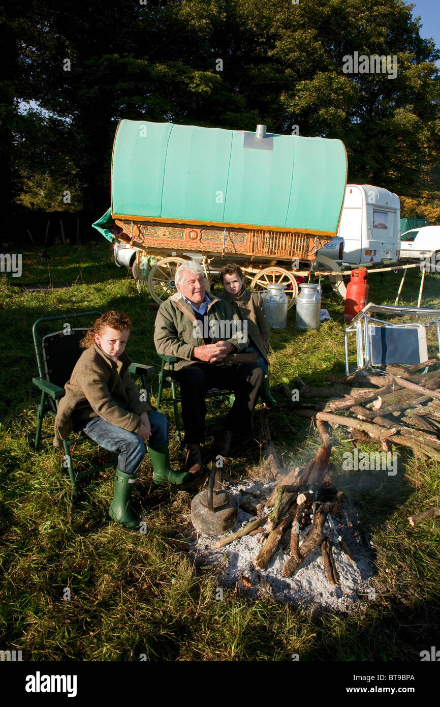 An elderly gypsy man sits with his grand children in front of his fire ...