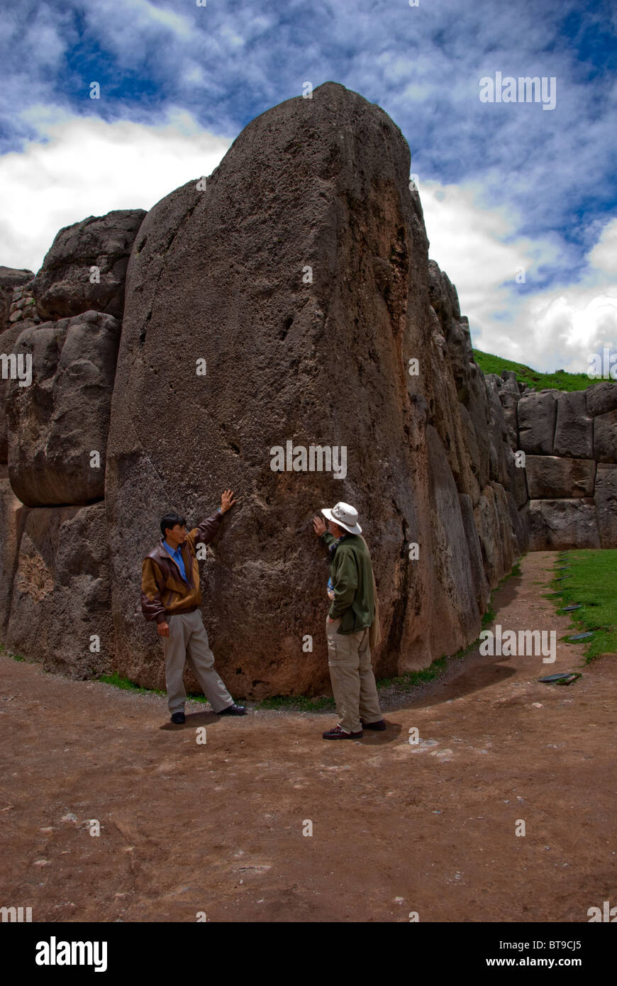 Peru, Cusco, Saqsaywaman Inca ruins. Two men compare their height to ...
