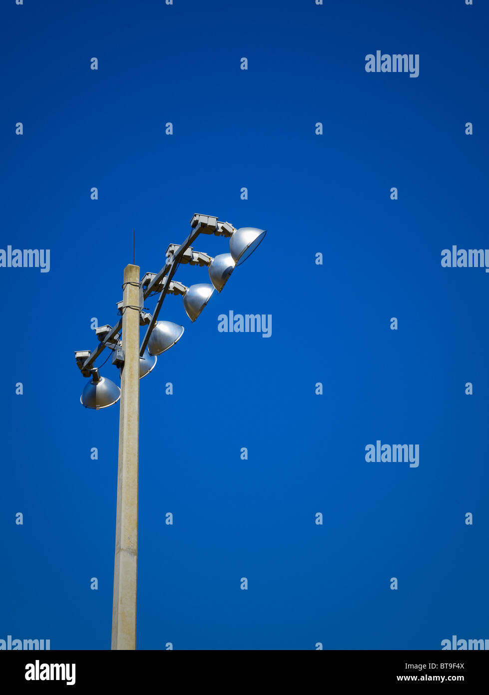 A single, modern, concrete re-enforced pole of lights in a sports field ...