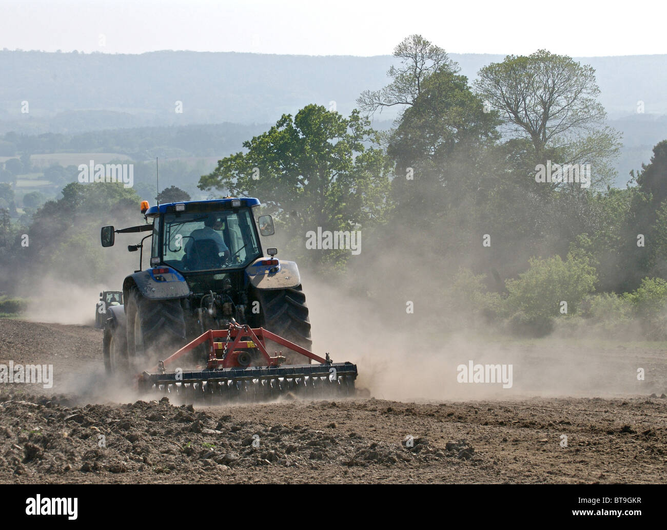 Tractor working on dry land in Sussex pulverising the soil and creating ...