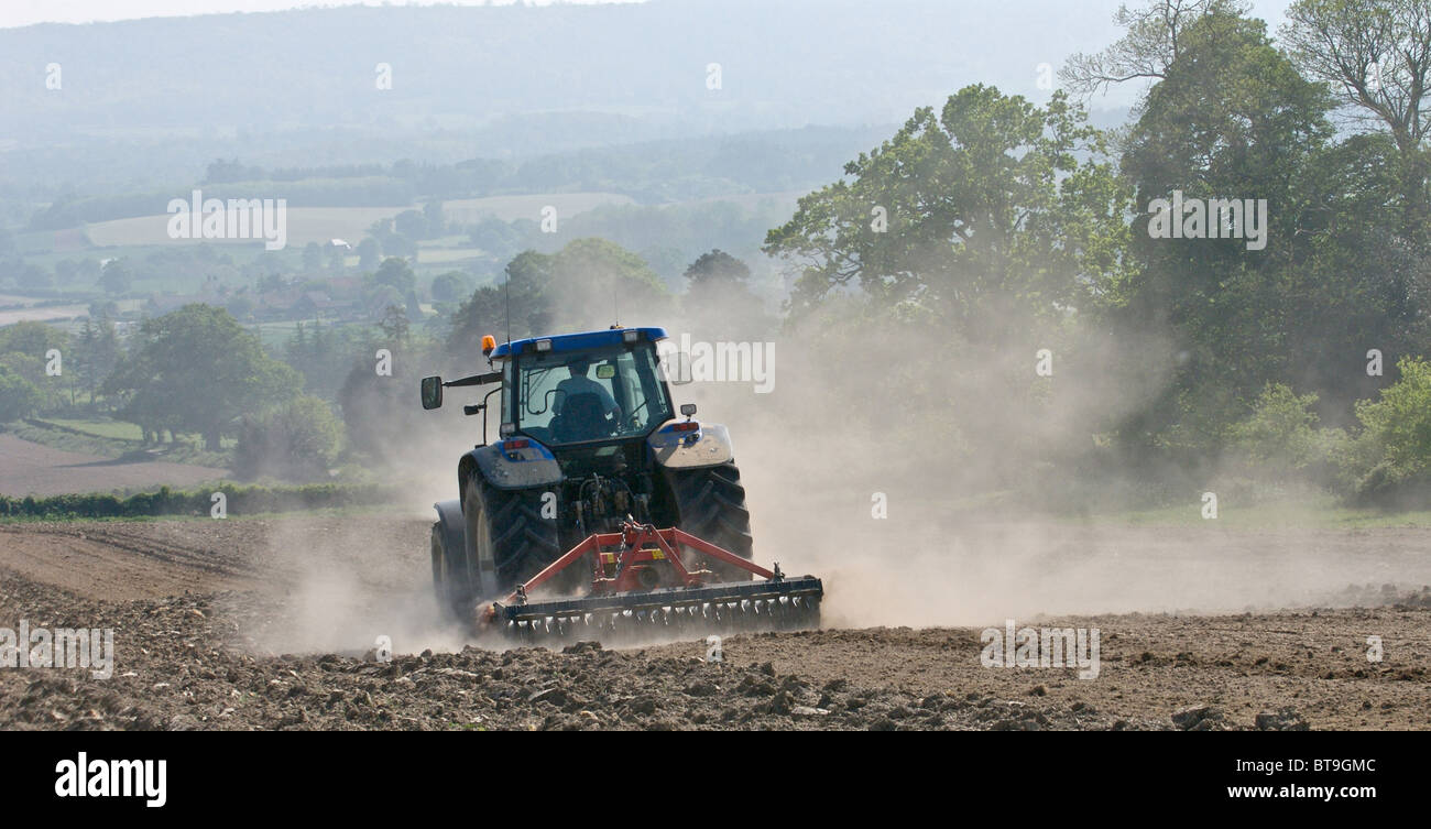 Tractor working on dry land in Sussex pulverising the soil and creating ...